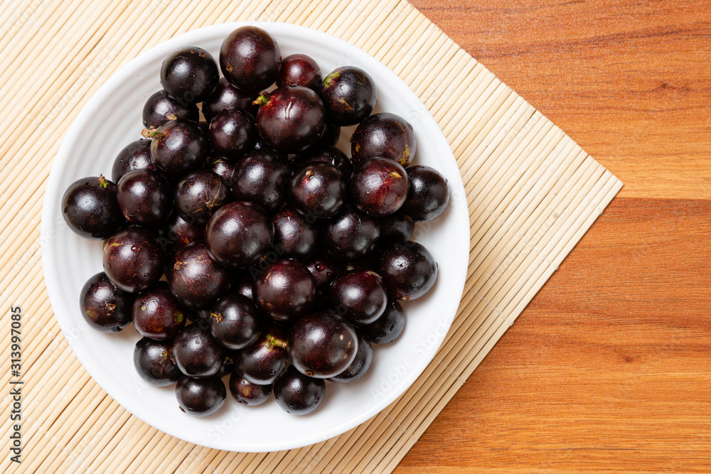 Jabuticaba in the bowl on wooden table - top view. Jaboticaba or ...