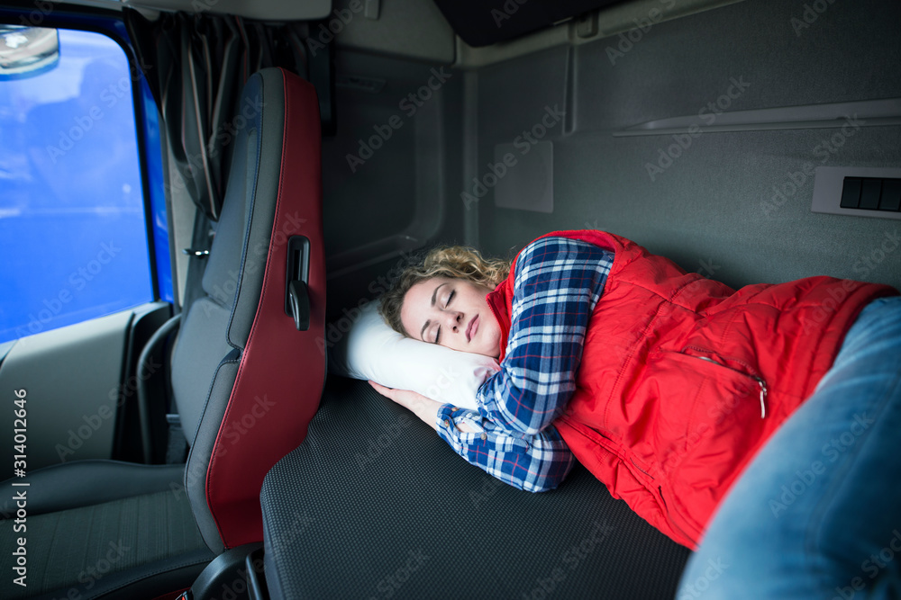 Shot of tired truck driver sleeping in cabin of his truck due to ...