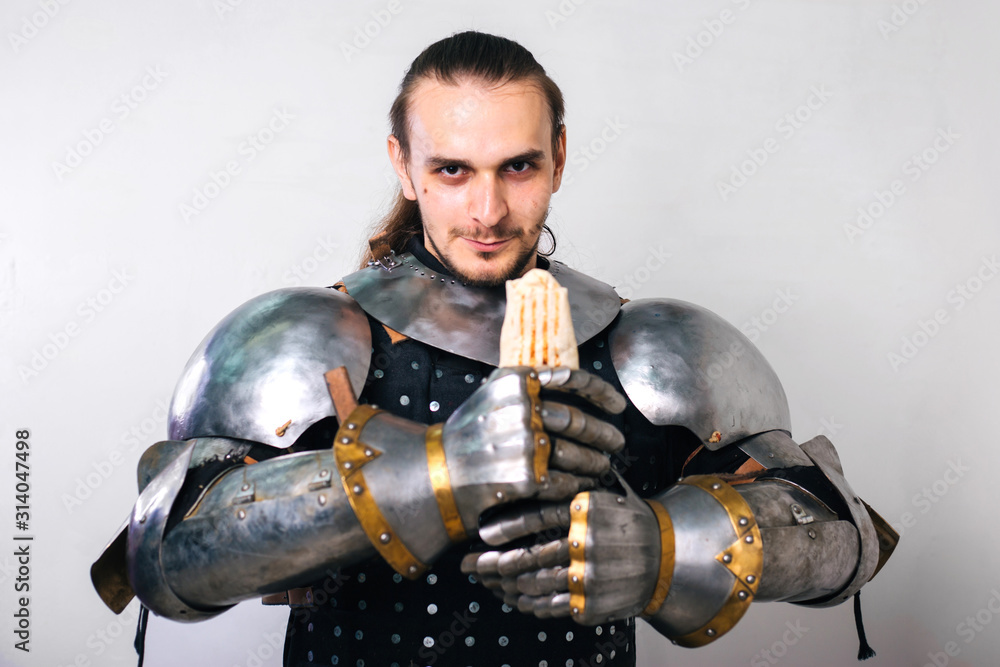 Knight with shawarma in his hands. A man in armor eats fast food. On a ...