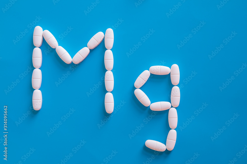 Magnesium tablets in a shape of Mg element on blue background Stock ...