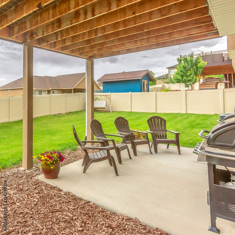 Square frame Patio at the backyard of a home with roof columns chairs ...