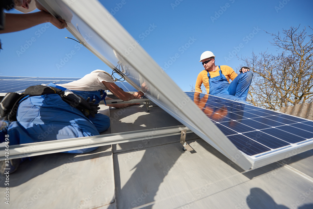 Male workers installing stand-alone solar photovoltaic panel system ...