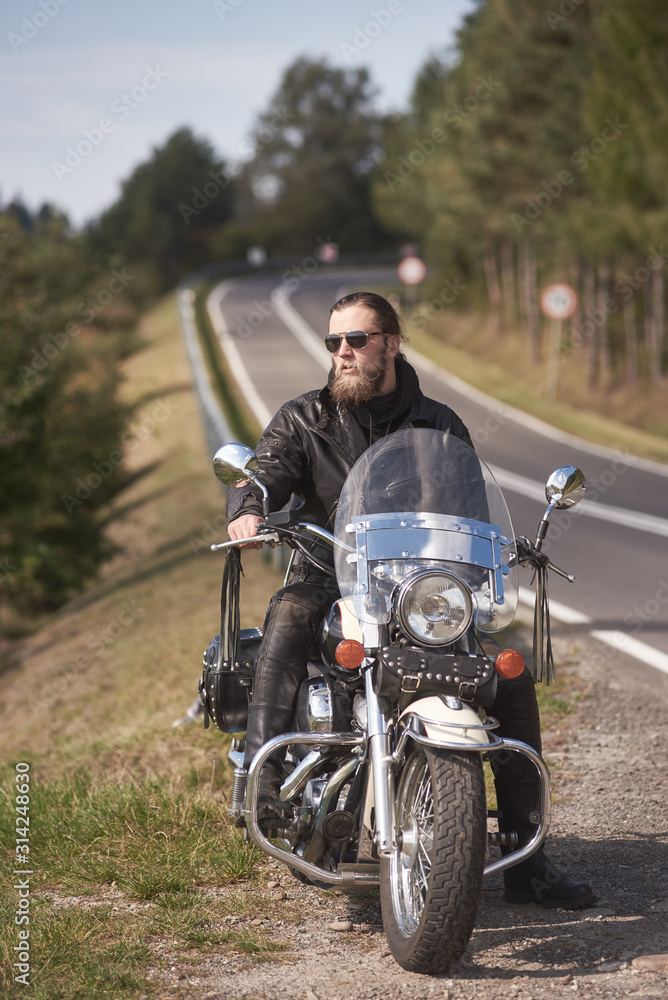 Handsome bearded biker with long hair in black leather jacket and ...