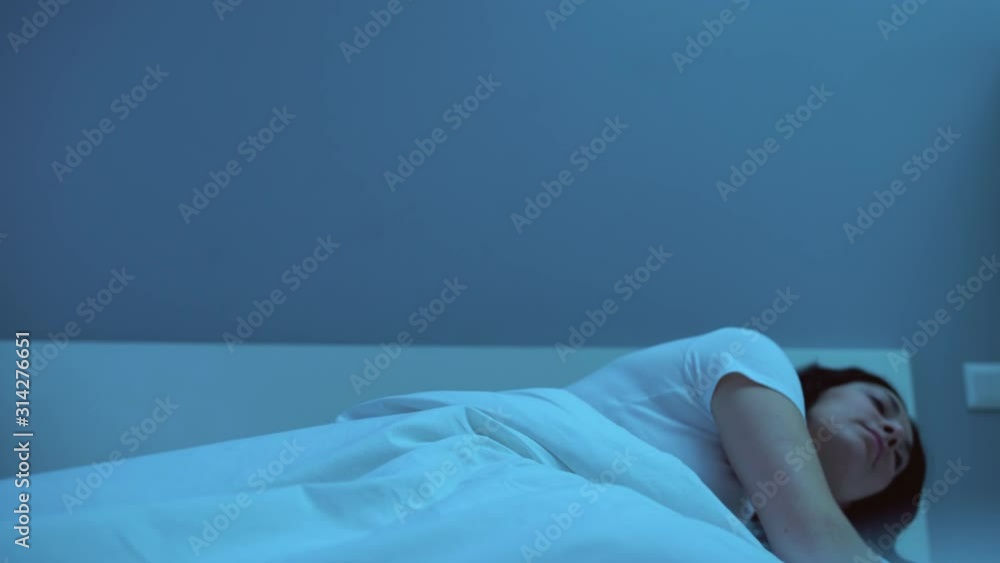 Exhausted young woman falling asleep in bed at night, tired after ...