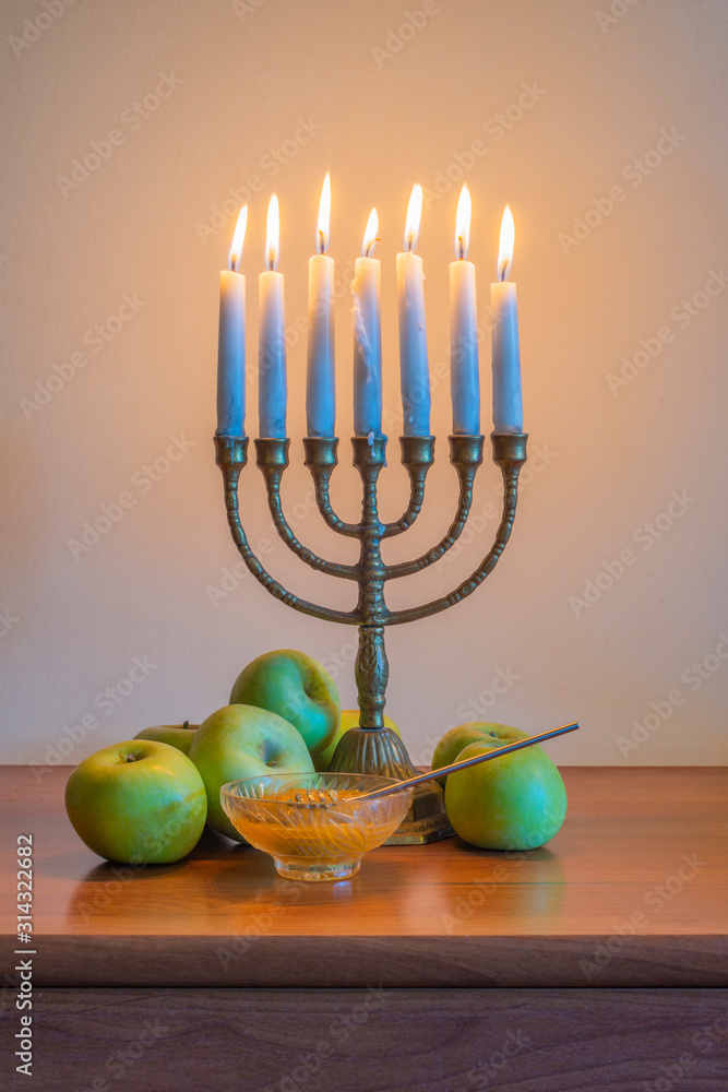 traditional Jewish menorah with burning candles, apples and a glass ...