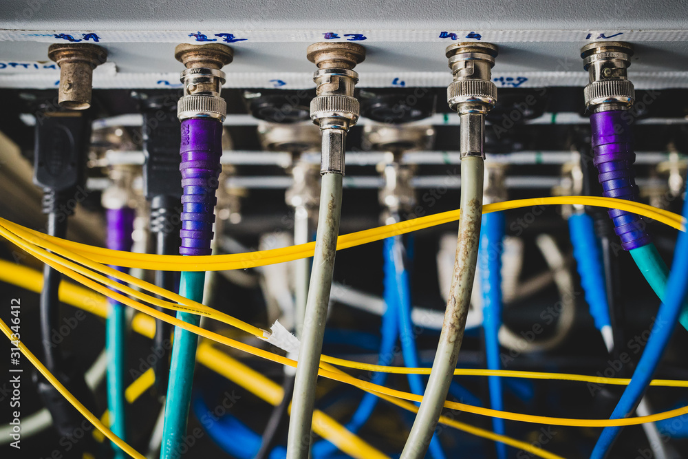 Blue BNC SDI signal cables plugged in the back of a patch panel viewed ...