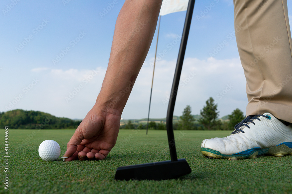 Golfer using pin marking position of golf ball on green. Stock Photo ...