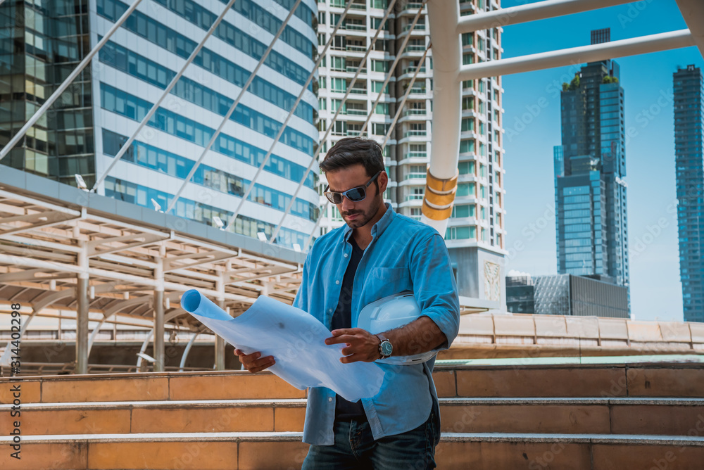 A Engineer talking smart phone ,look at project blueprints for thinking ...