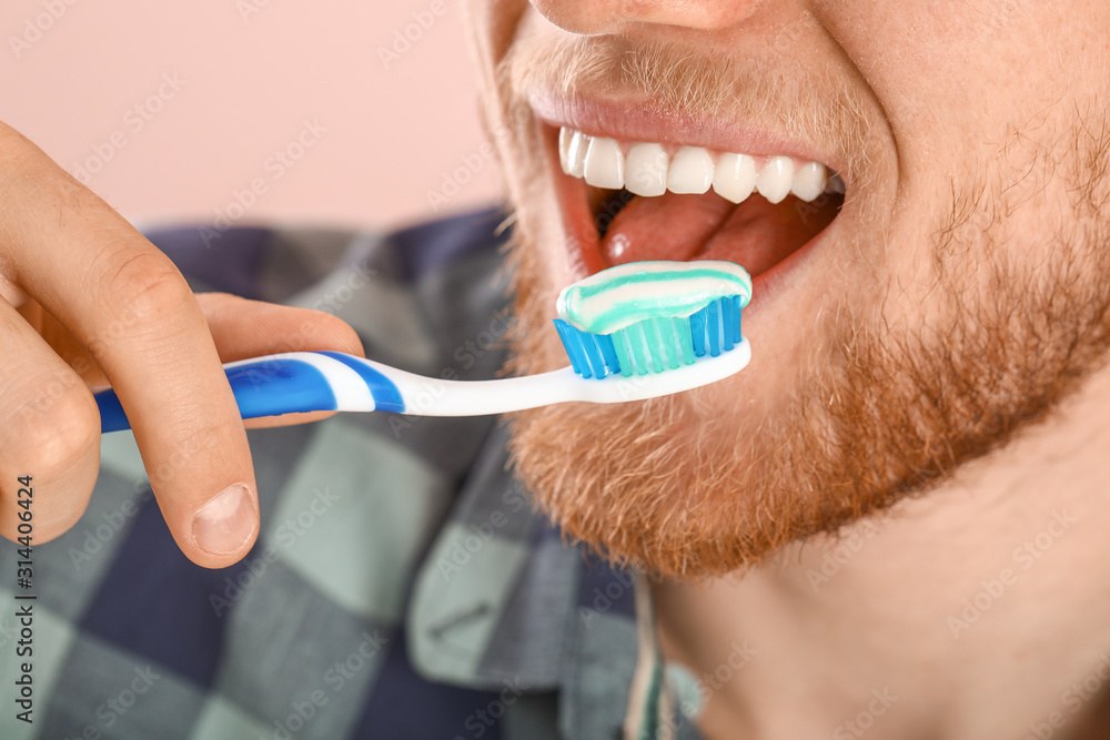 Young man brushing teeth on color background, closeup Stock Photo ...