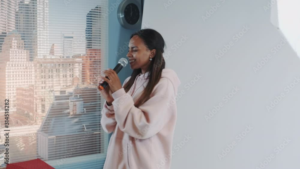 Close-up of attractive multiethnic woman posing with microphone on ...