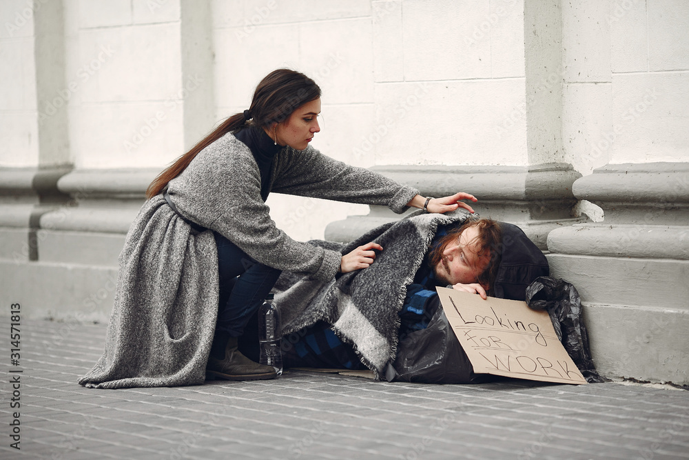 Homeless in a city. Man asking for food. Man with a tablet. Girl ...