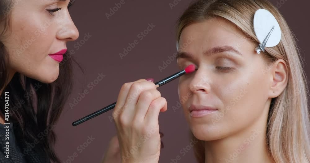 Video Stock Makeup artist applies a special brush foundation on the ...