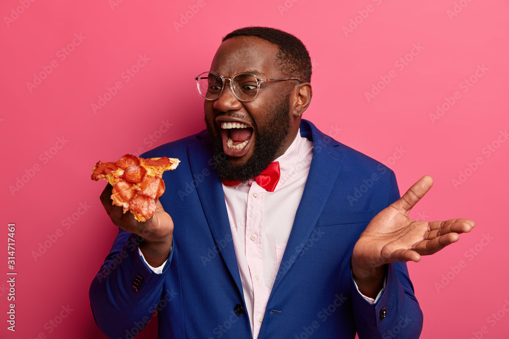Hungry black man bites very big piece of pizza, has appetite, wears ...