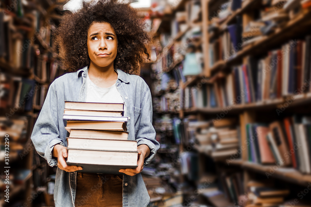 Heavy book pile in his hands, a young girl, an African-American student ...