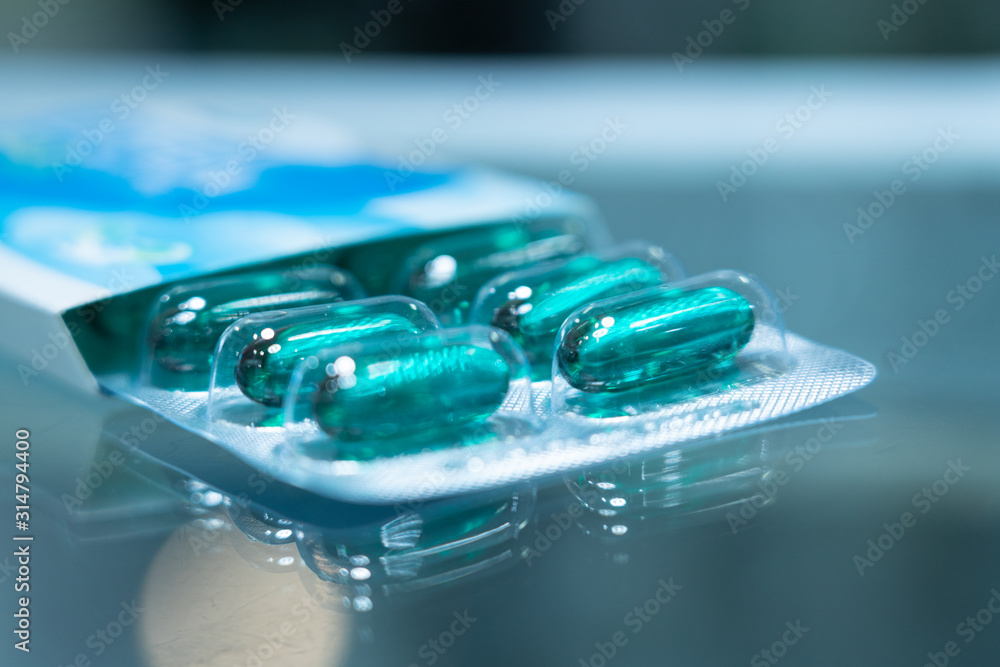 Blue soft gel capsule medicine in strip package with blur background ...