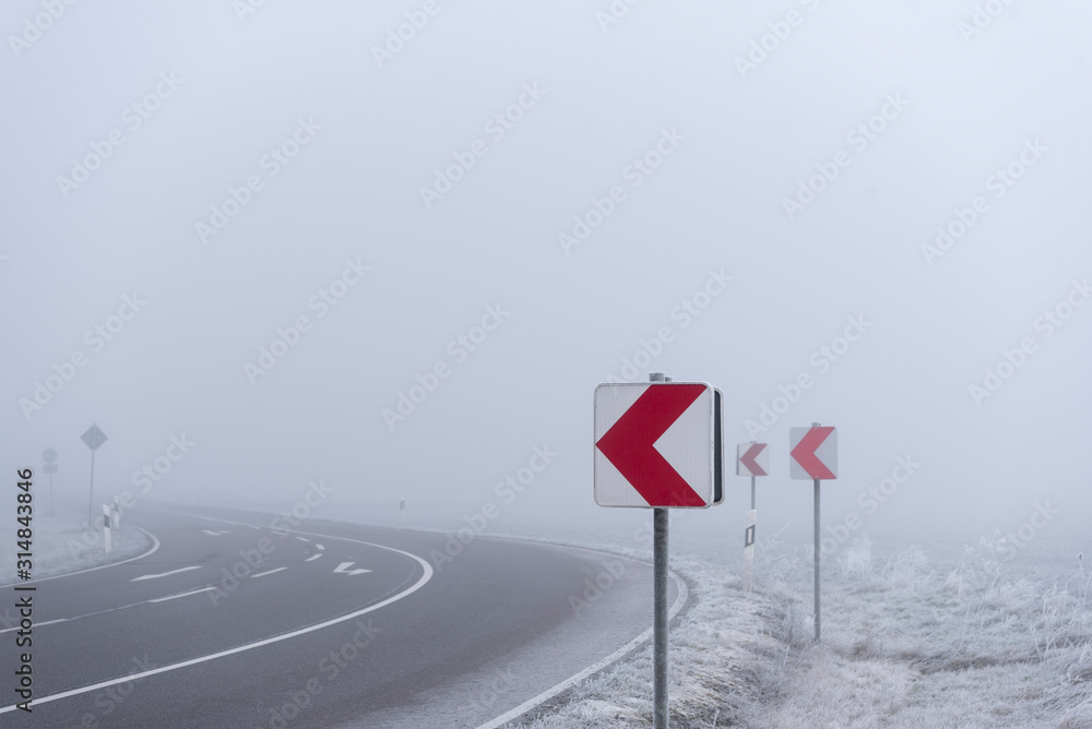 Warning road signs before dangerous curve in dense mist Stock Photo ...
