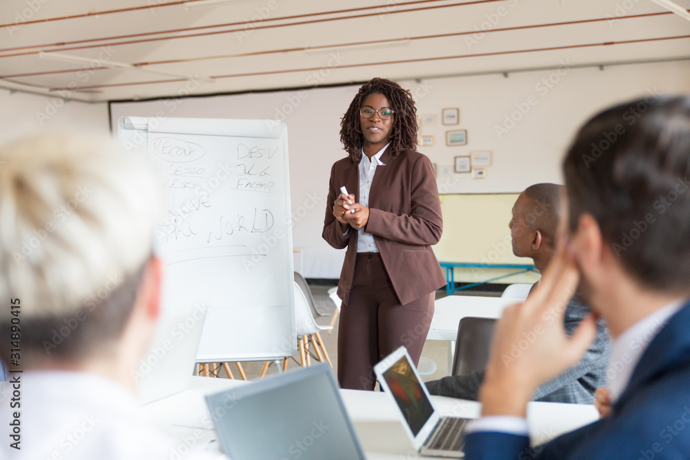 Smiling speaker standing and lecturing on business conference. Group of ...