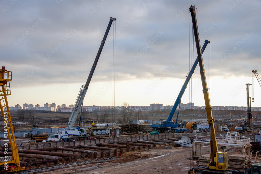 Mobile auto cranes working at construction site. Digging a pit for the ...
