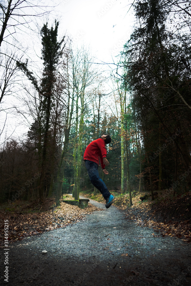 Man jumping and levitating in the middle of a road in the forest with ...