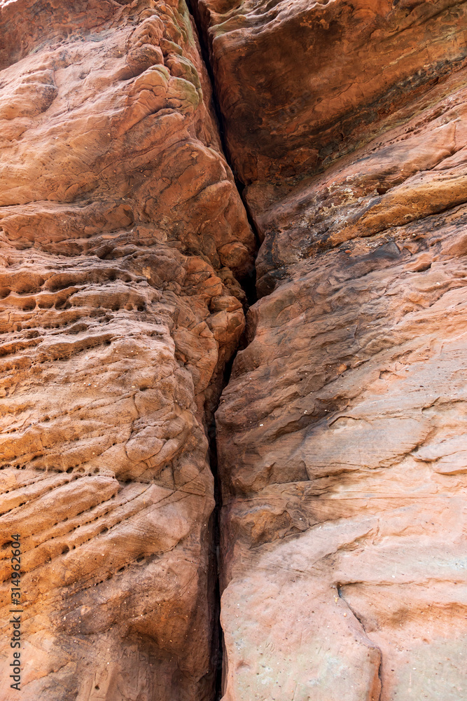 A large crack in the rock. Rocks of red and orange sandstone with ...