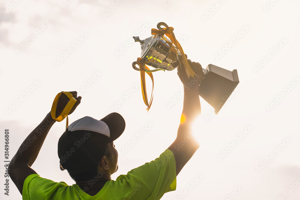 sport man holding up a sillver trophy cup as a winner. Champion trophy ...