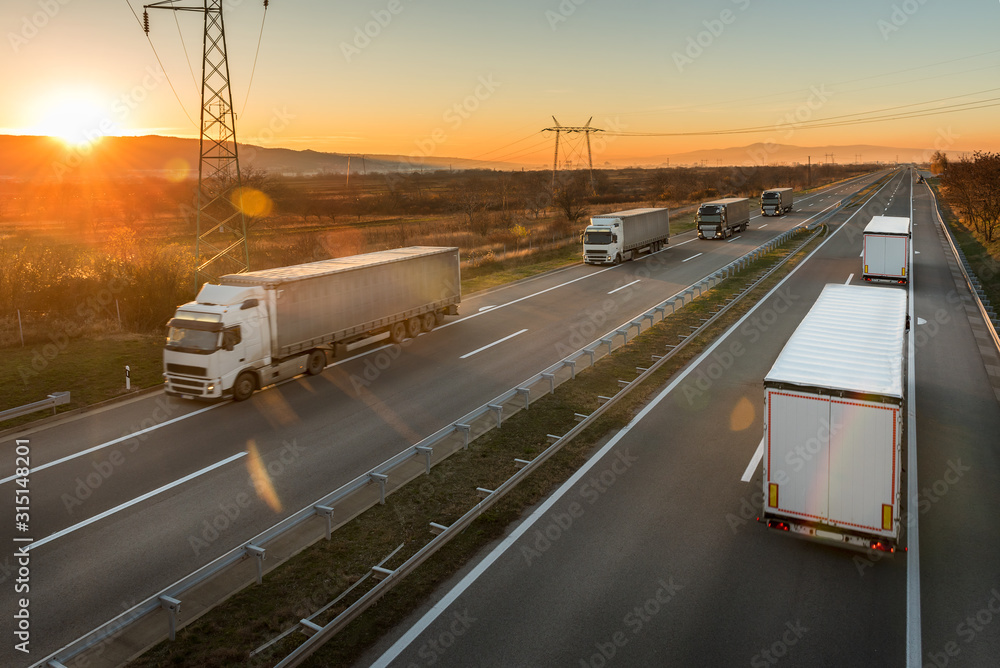 Convoys of transportation trucks passing each other on a highway ...