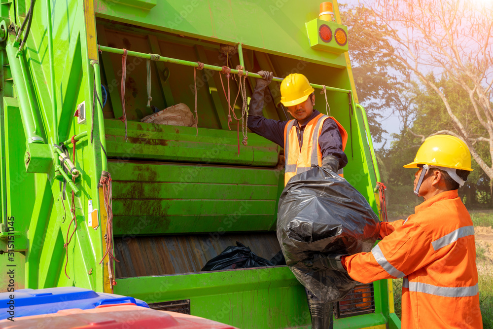 Two garbage men working together on emptying dustbins for trash removal ...