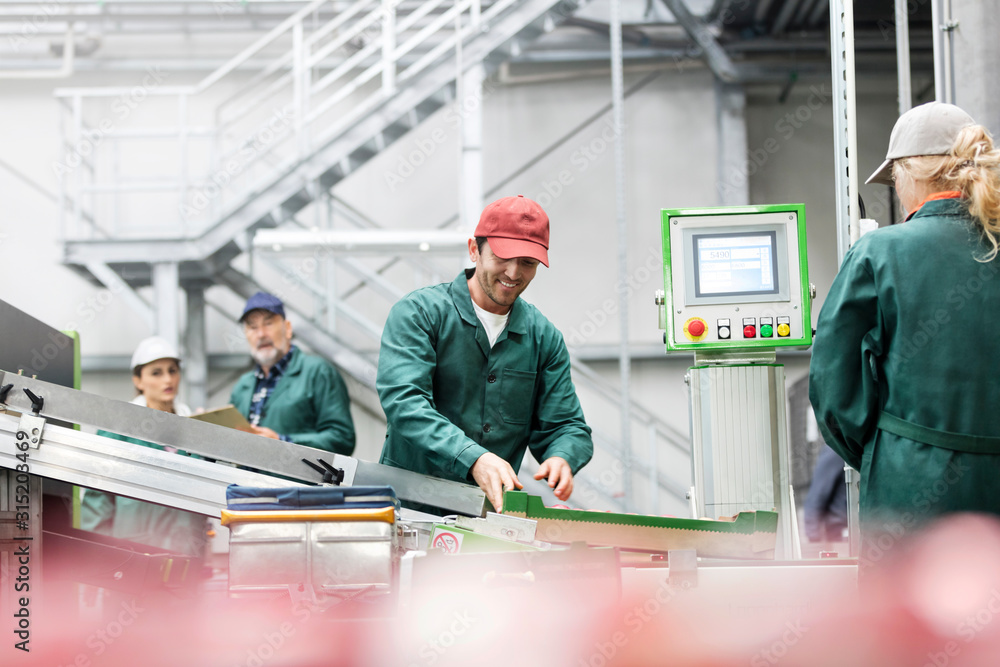 Smiling worker at conveyor belt in food processing plant Stock Photo ...