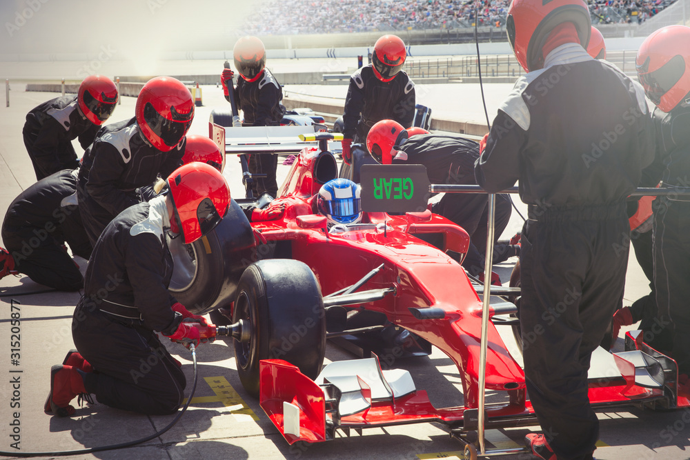 Pit crew replacing tires on formula one race car in pit lane Stock ...