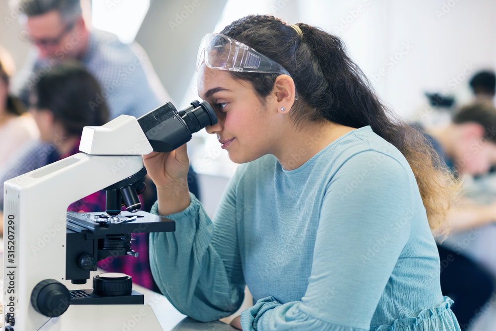 Girl student using microscope, conducting scientific experiment in ...