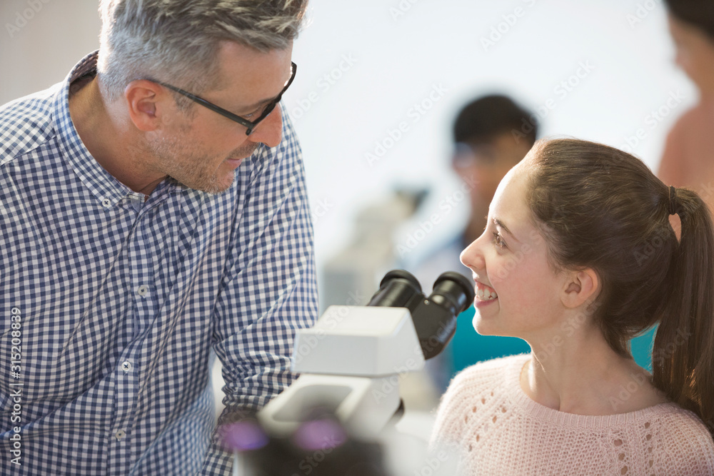Male teacher and smiling girl student conducting scientific experiment ...