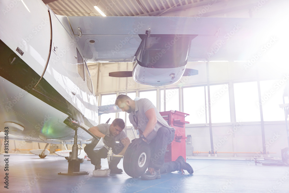 Male mechanics fixing wheels on airplane in hangar Stock Photo | Adobe ...