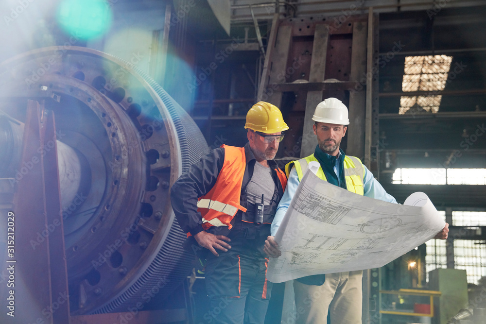 Engineers reviewing blueprints in steel factory Stock Photo | Adobe Stock