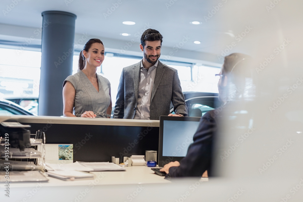 Couple at reception desk in car dealership showroom Stock Photo | Adobe ...