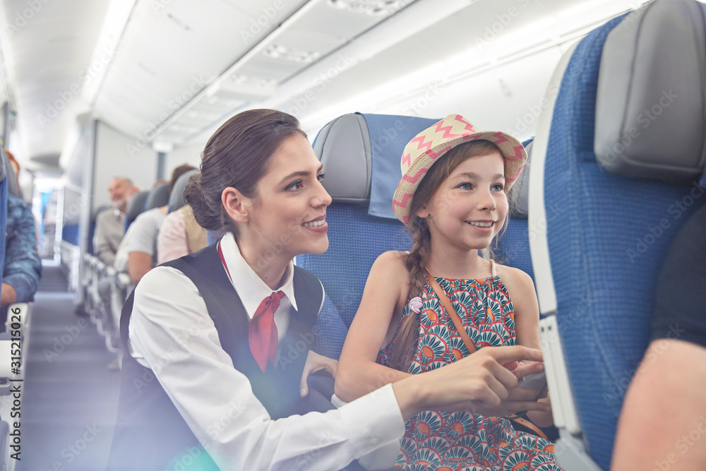 Female flight attendant helping girl on airplane Stock Photo | Adobe Stock