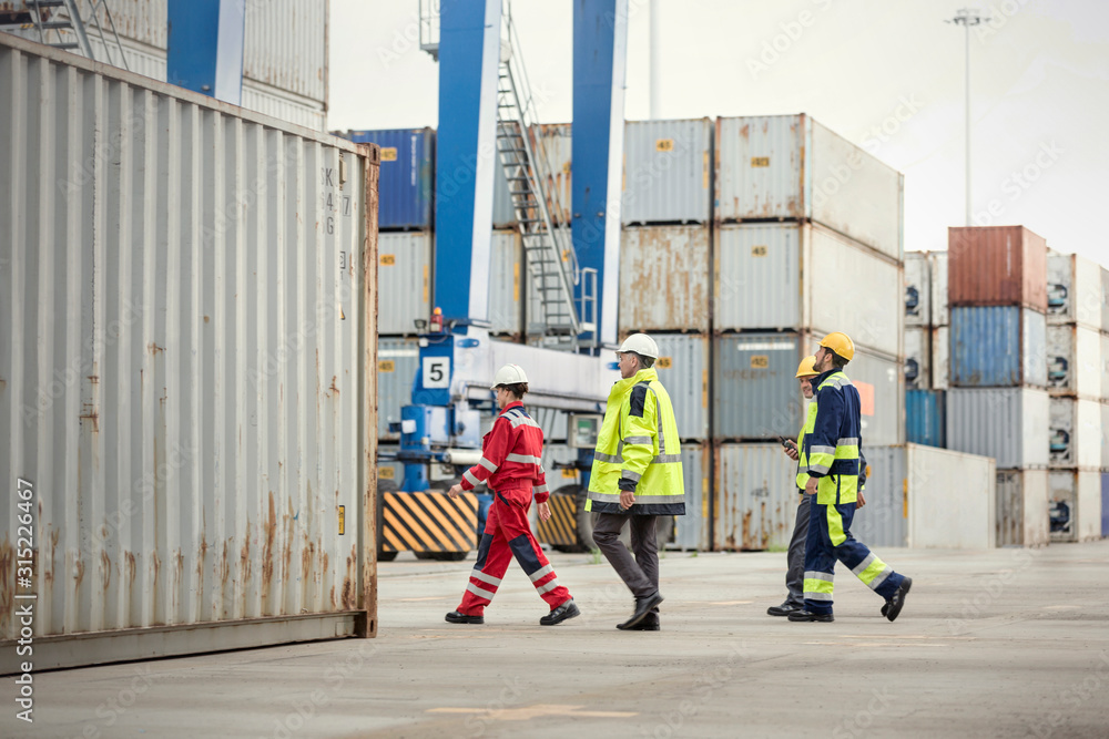 Dock workers walking along cargo containers at shipyard Stock Photo ...