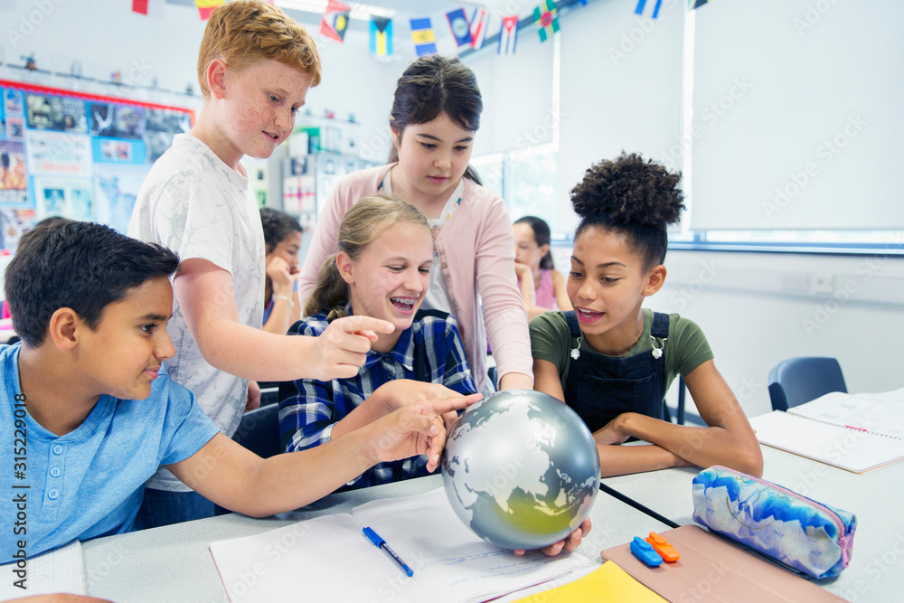 Curious junior high school students looking at globe in classroom Stock ...