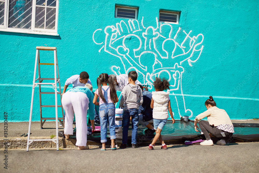 Kid volunteers painting community mural on sunny wall Stock Photo ...