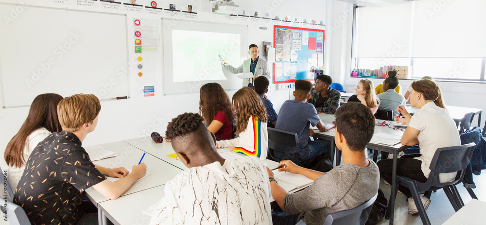 High school students watching teacher at projection screen during ...