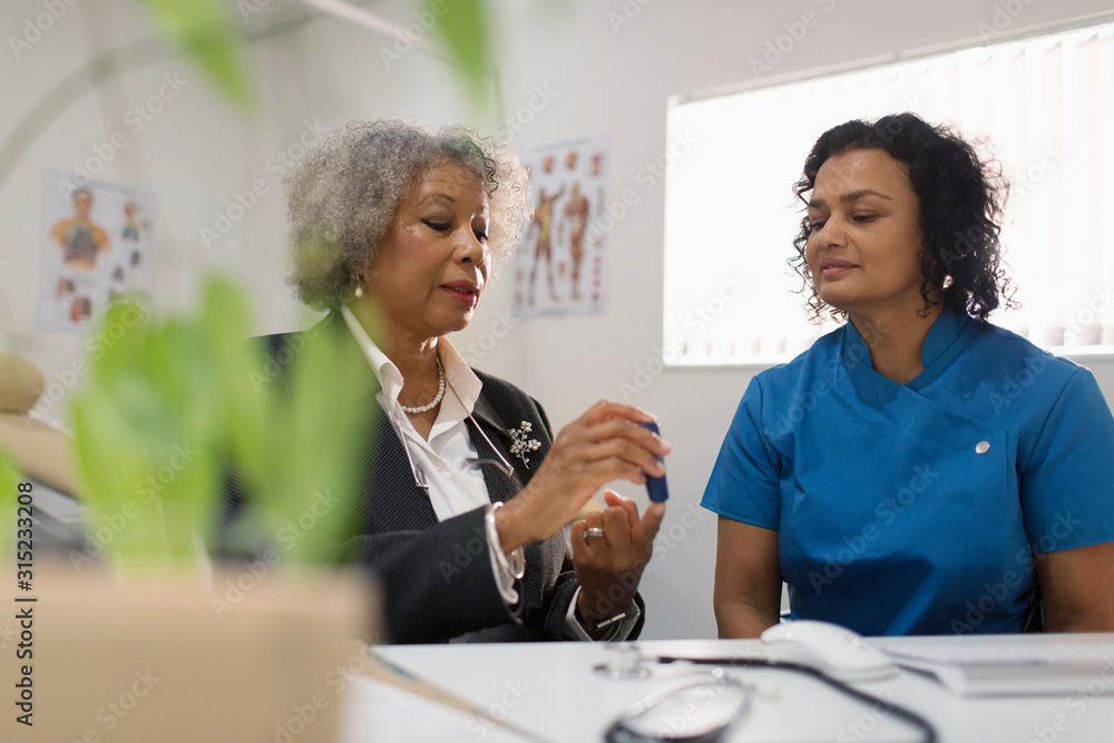 Female doctor teaching diabetic patient how to use glucometer in ...