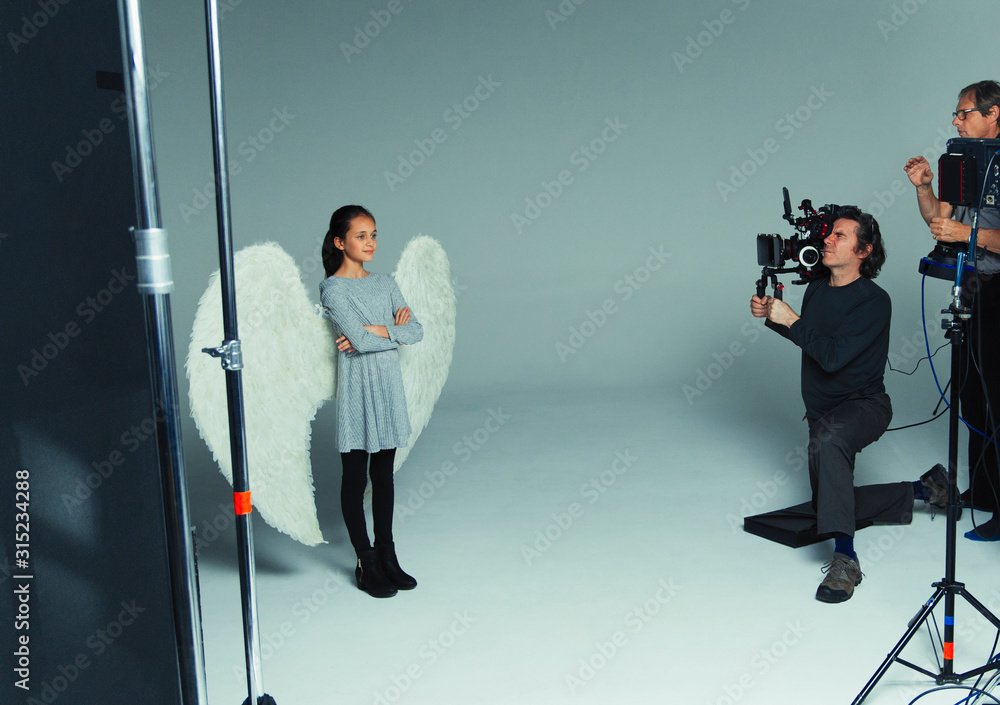 Girl in angel wings posing for photographers during photo shoot in ...