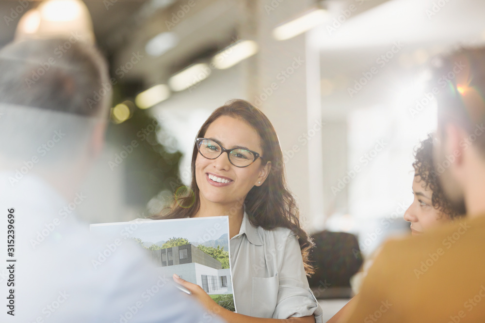 Smiling architect showing drawings to colleagues in meeting Stock Photo ...