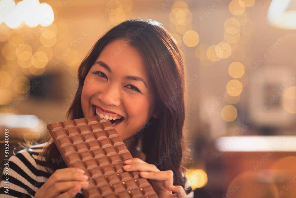 Portrait woman with sweet tooth craving biting into large chocolate bar ...