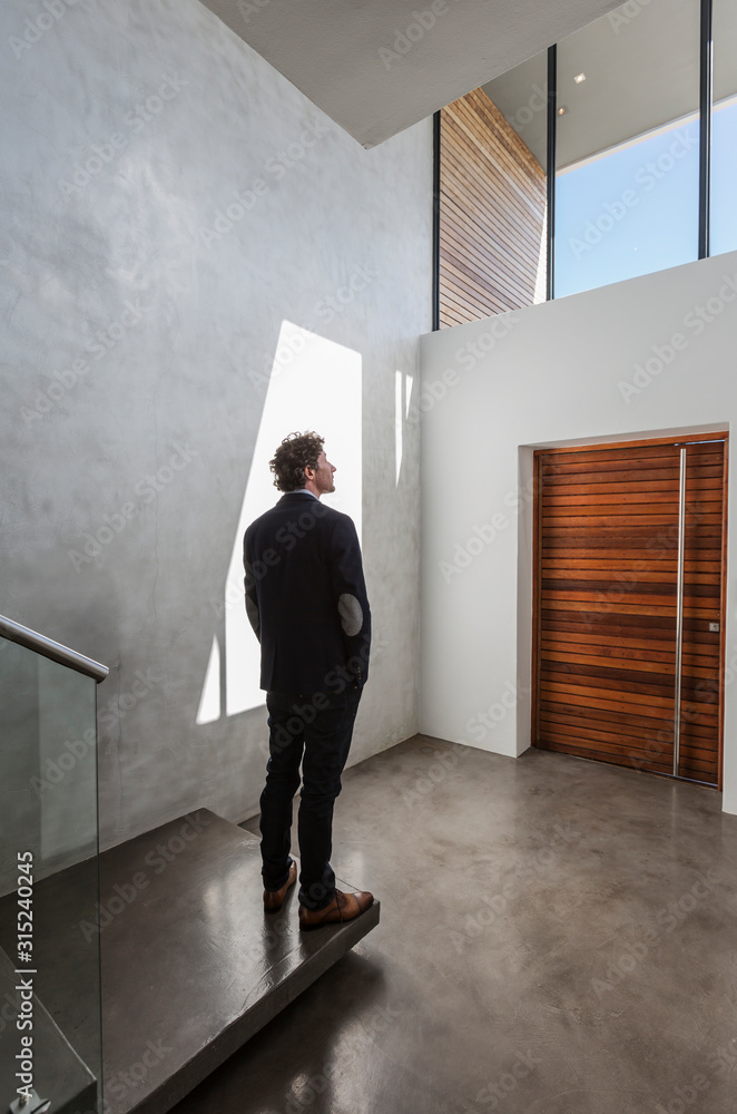 Pensive businessman standing in modern home showcase interior foyer ...