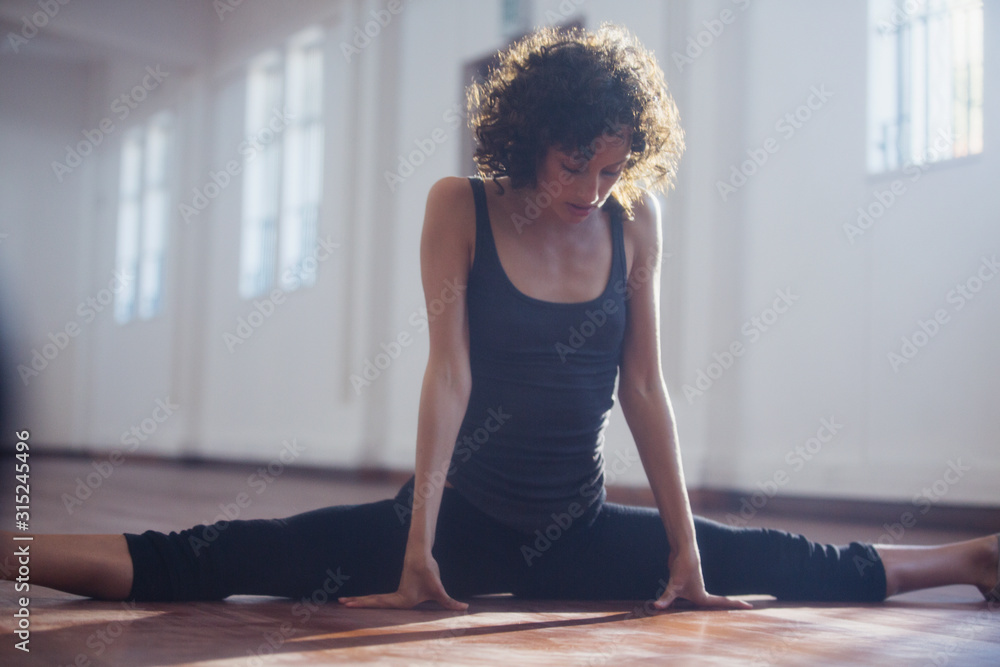 Strong young female dancer stretching, doing the splits in dance studio ...