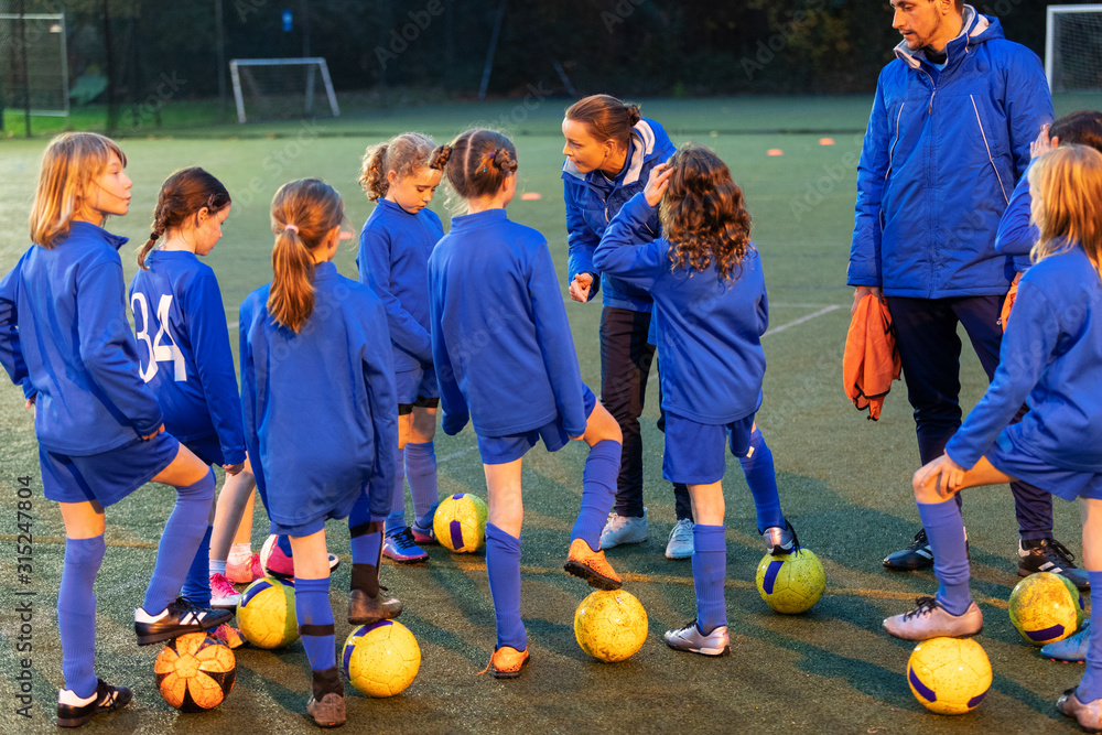 Girls soccer team listening to coaches on field Stock Photo | Adobe Stock