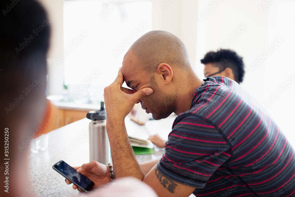 Man with head in hands using smart phone Stock Photo | Adobe Stock