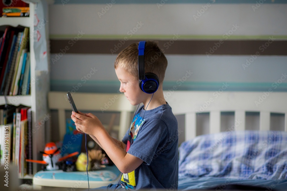Boy wearing headphones using device Stock Photo | Adobe Stock