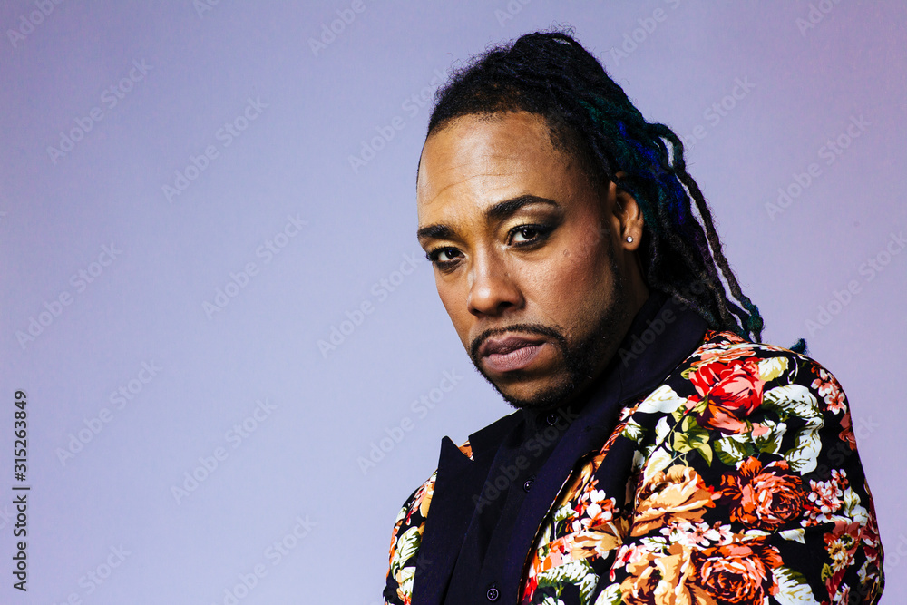 Studio portrait of a man wearing a flower patterned suit and dreadlocks ...