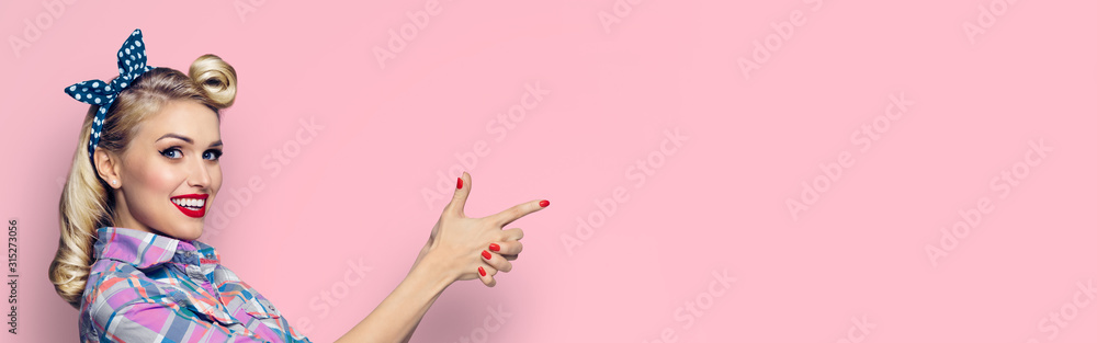 Smiling woman pointing at something. Excited girl in pin up cloth ...